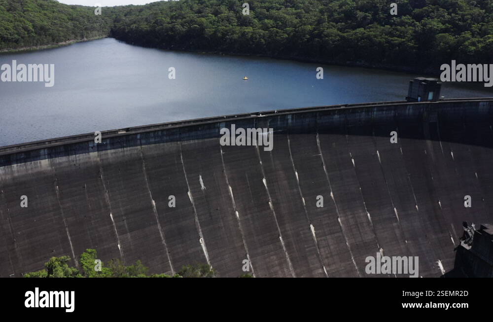 Drone aerial pan up showing large dam full of water surrounded by ...
