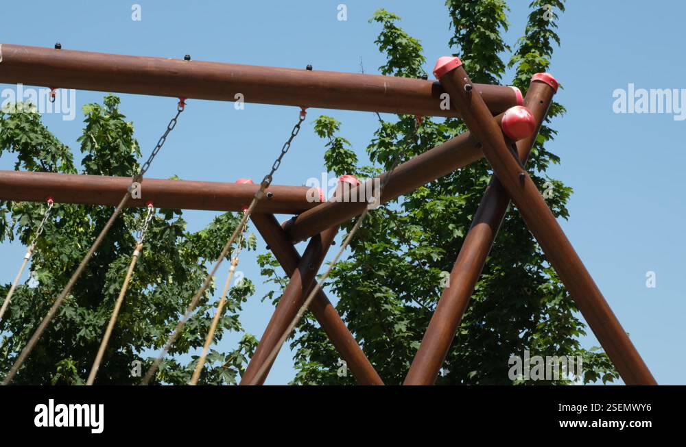 playground, big swing ropes swing back and forth between blue sky and ...
