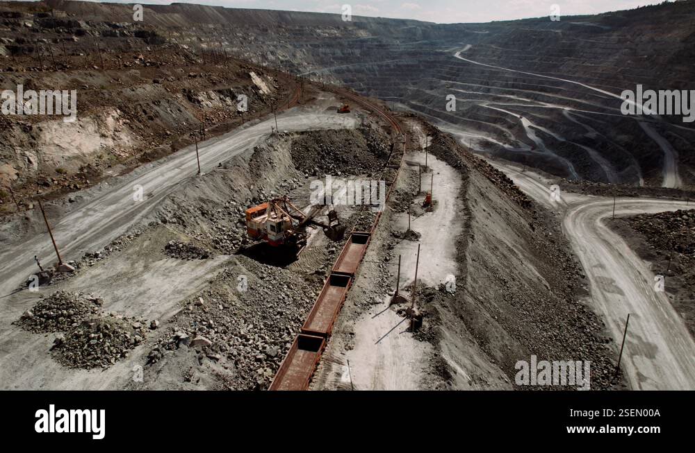 Excavator loads iron ore into a freight train. Mining industry concept ...