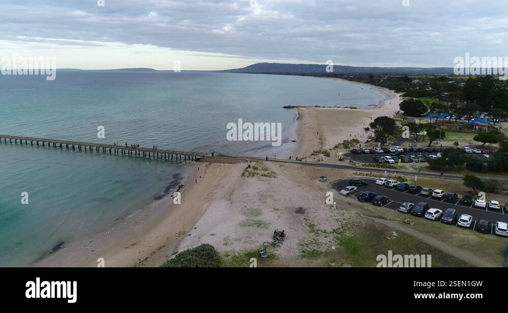 Drone overlooking beach foreshore and car park pier dusk dolly forward ...