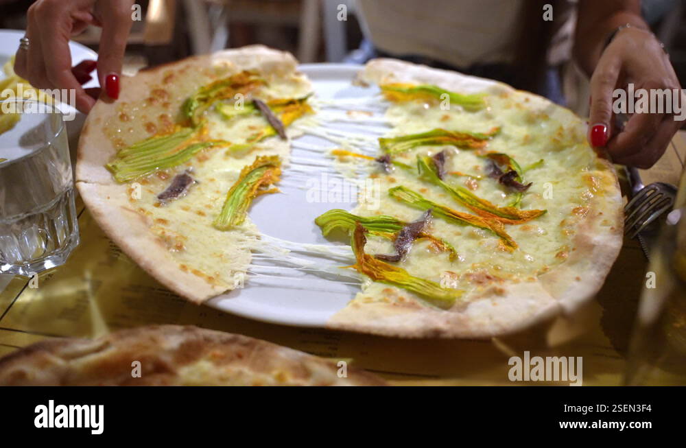 Hungry woman dividing crusty Italian pizza with melted cheese, pepper ...