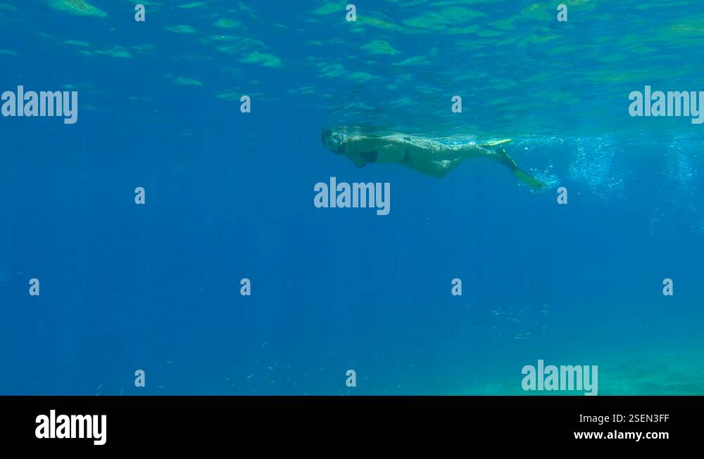 Woman in mask and fins swim in the blue water. Underwater shot ...