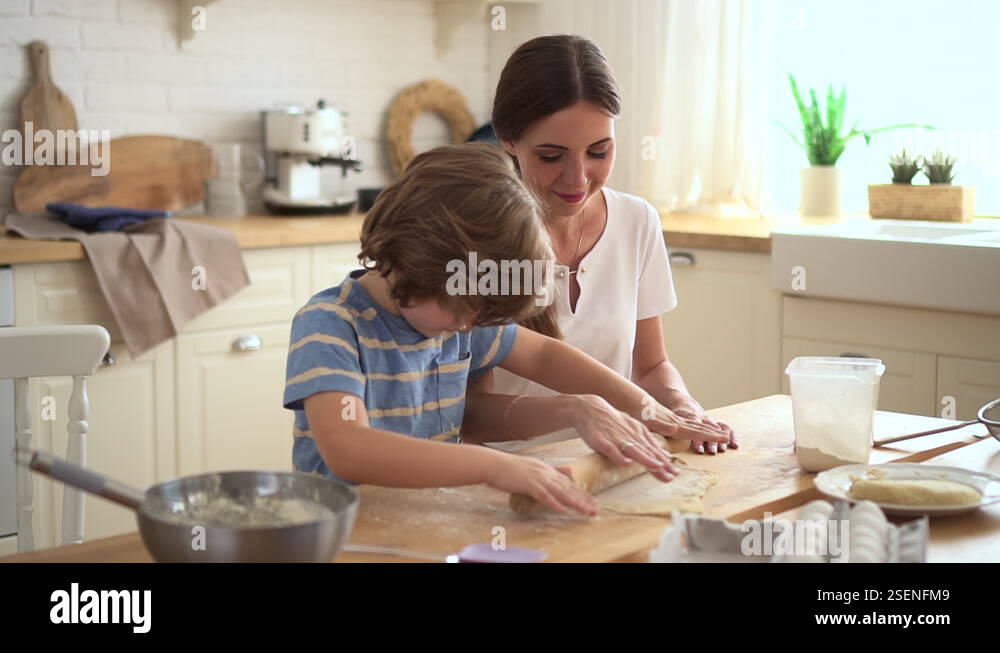 Family cooking in kitchen. Mother teaches son to make pie woman with ...