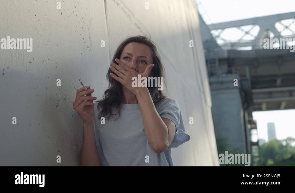 sad woman is smoking cigarette outdoors, standing alone and crying ...