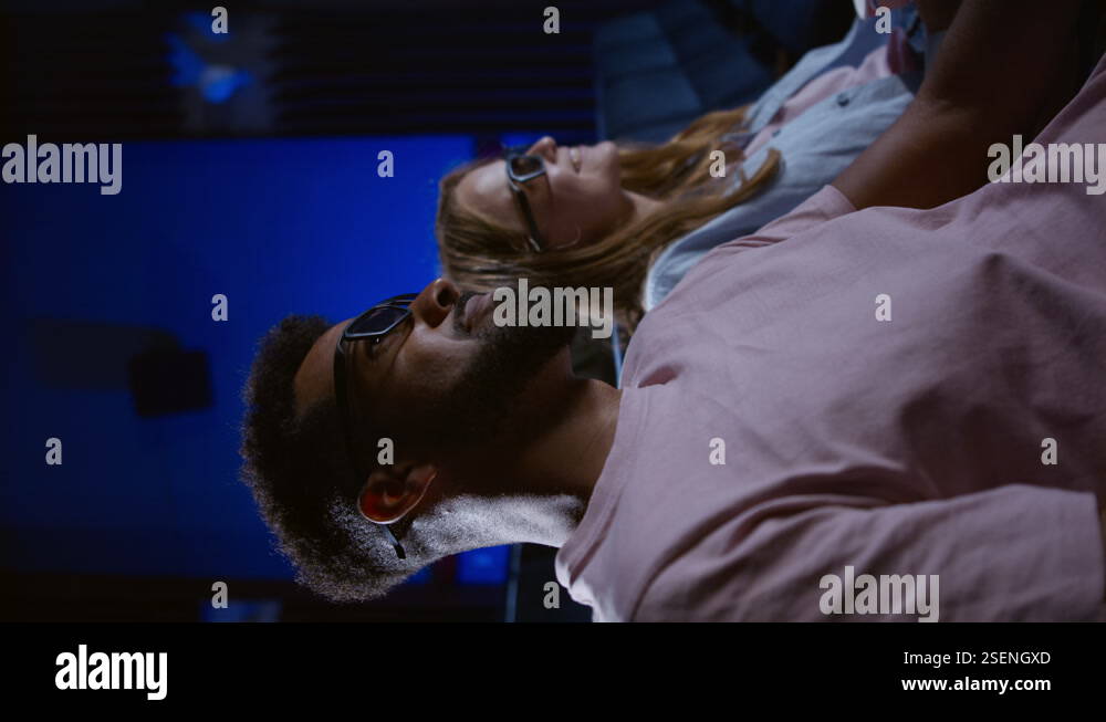 Vertical footage of cheerful young couple putting on 3d glasses in the ...