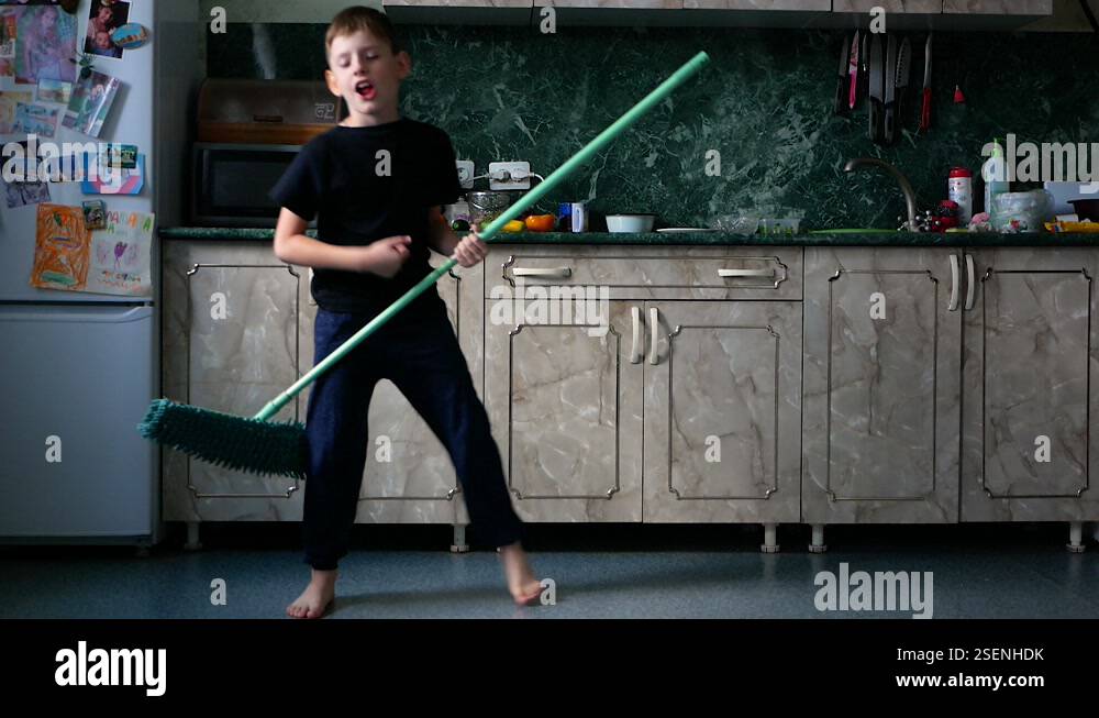 House cleaning with music. Caucasian boy of 6-8 years old with a mop in ...