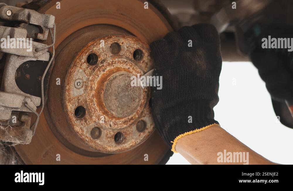 The repairman replaces the old brake disc and pads of the lifted car ...