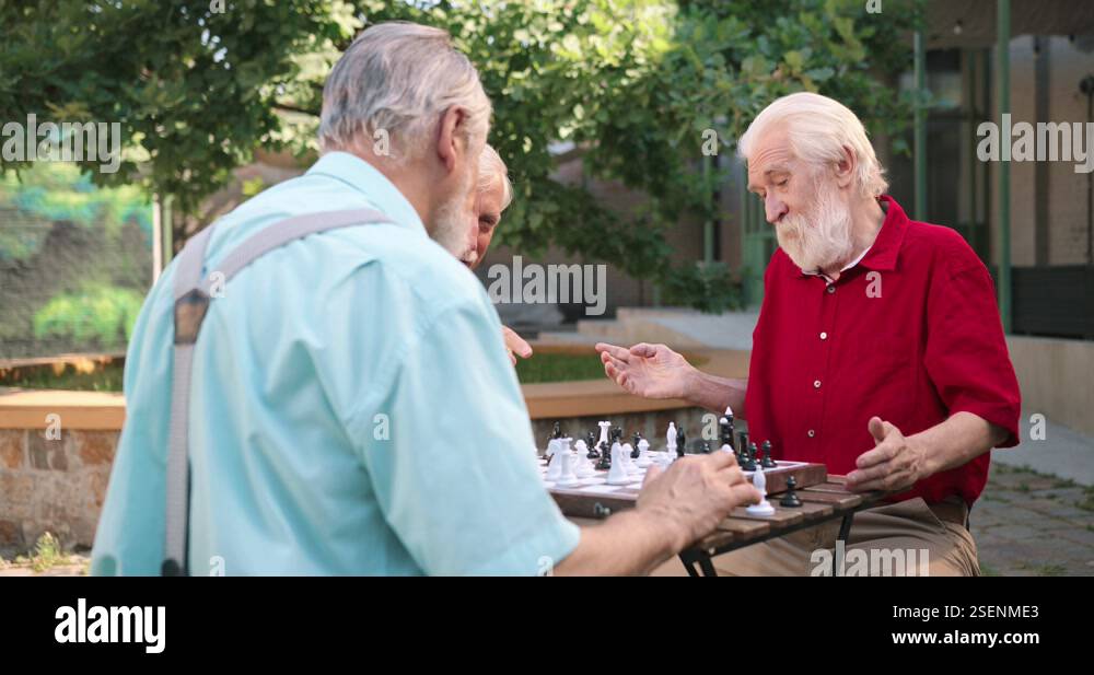Old male friends playing chess in the yard. One man preparing to doing ...