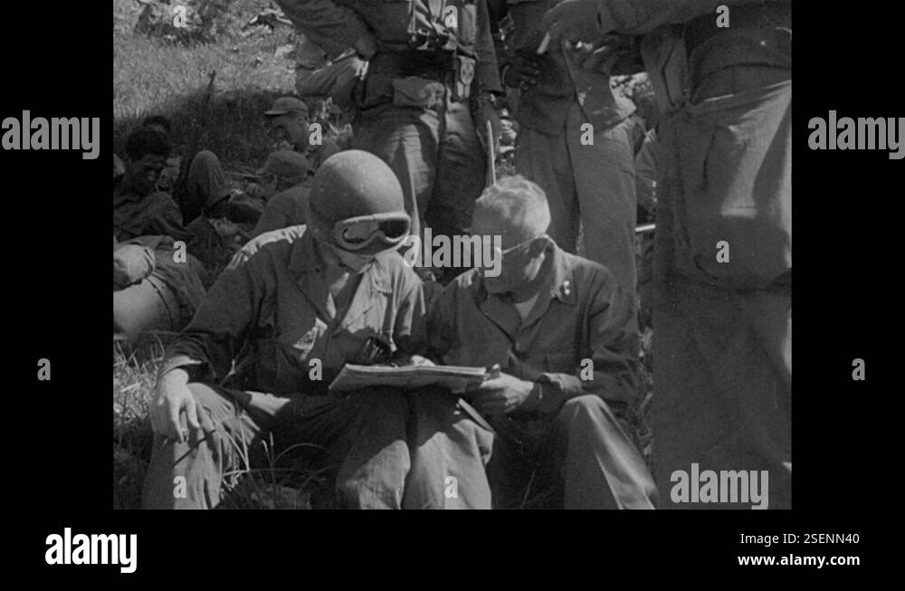 1950s: Tanks fire. Men study papers. Men walk down road. Men atop tank ...