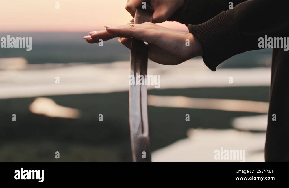 Young woman in black clothes passes her fingers against the blade of ...