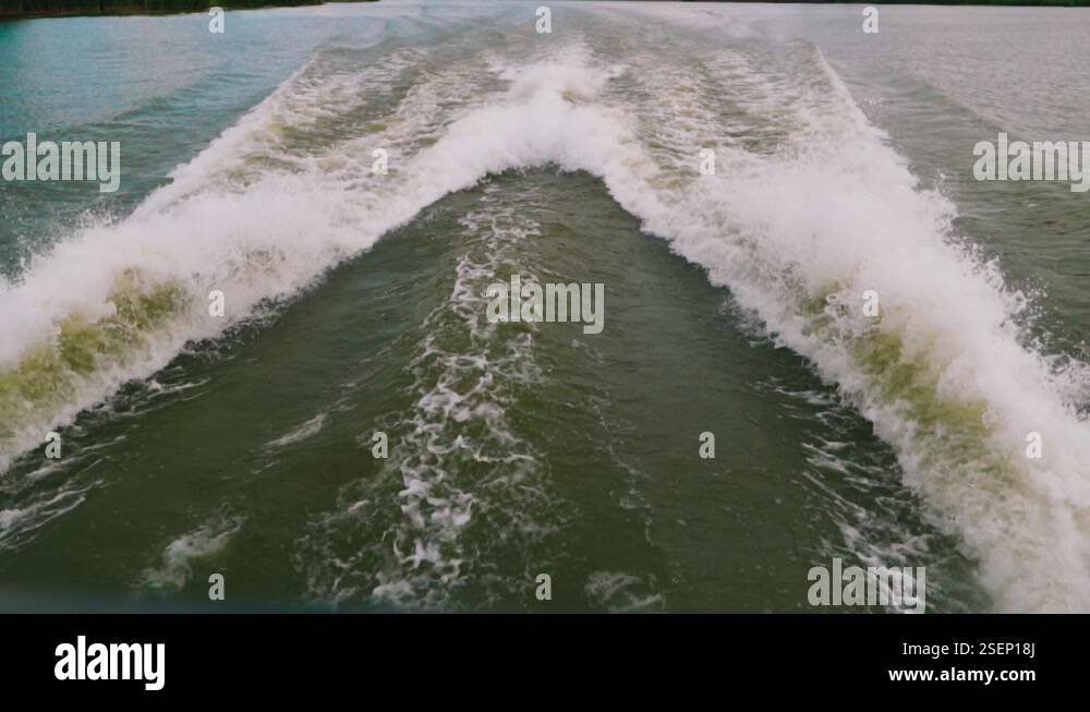 A speed boat and its engine propellers churn the water into waves and ...