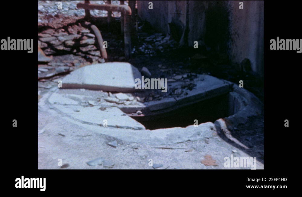 1940s: Hole in covering over well in ground. Caved-in side of building ...