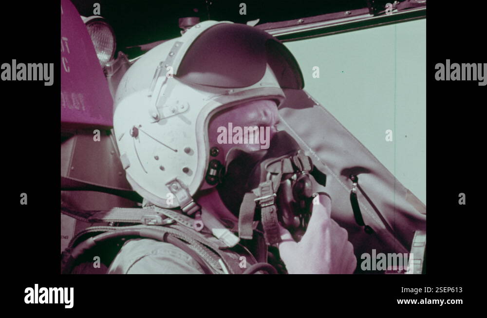 1960s: Slate. Pilot in a cockpit puts on a face mask and talks. Slate ...