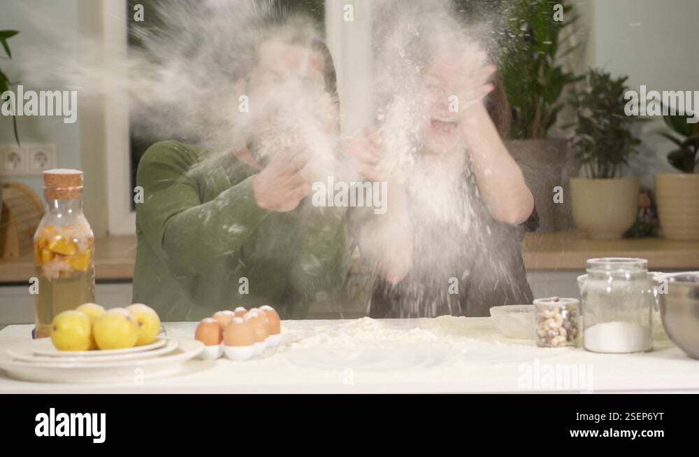 family is preparing flour dough in the kitchen. Happy men and women ...