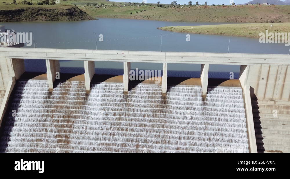Aerial. White water pours down concrete stepped dam wall spillway, in a ...