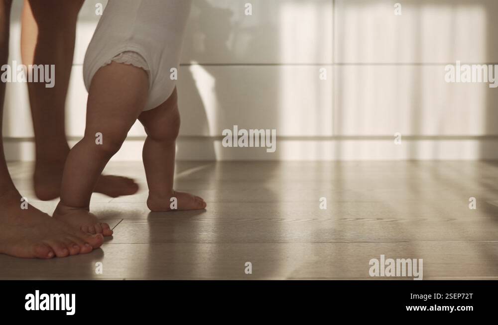 Baby taking first steps. The Mother holds and supports the child and ...
