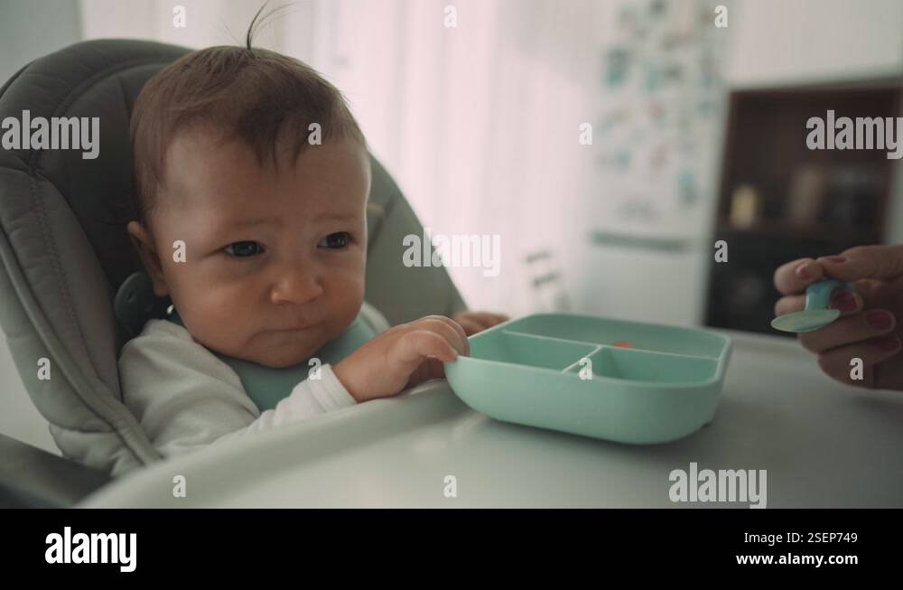 Parents feed the child with banana slices. The first complementary food ...