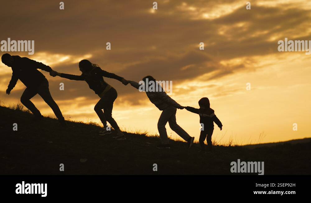 Giving a helping hand. Silhouette of family helping each other on top ...