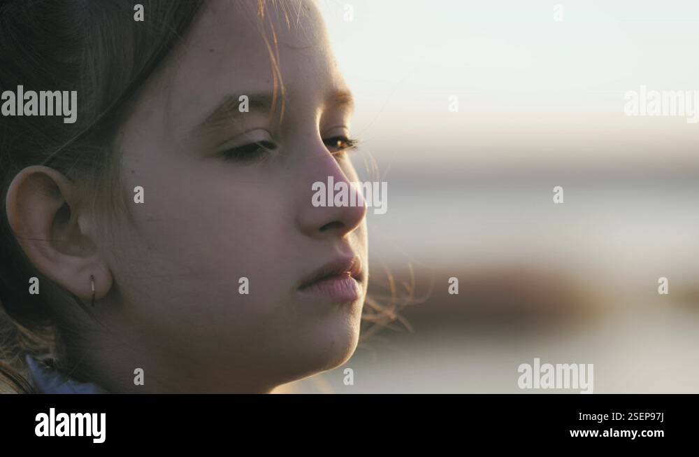 Profile of young girl looking up at sunset sky. Kid wants a dream come ...