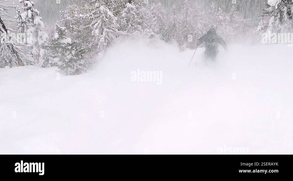 Two male ski friends skiing fresh powder deep snow off piste in the ...
