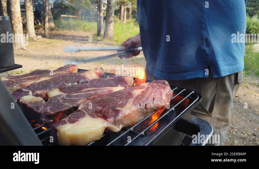 Man Grilling Steak While On Camping Trip - Flipping Steak On Griller By ...
