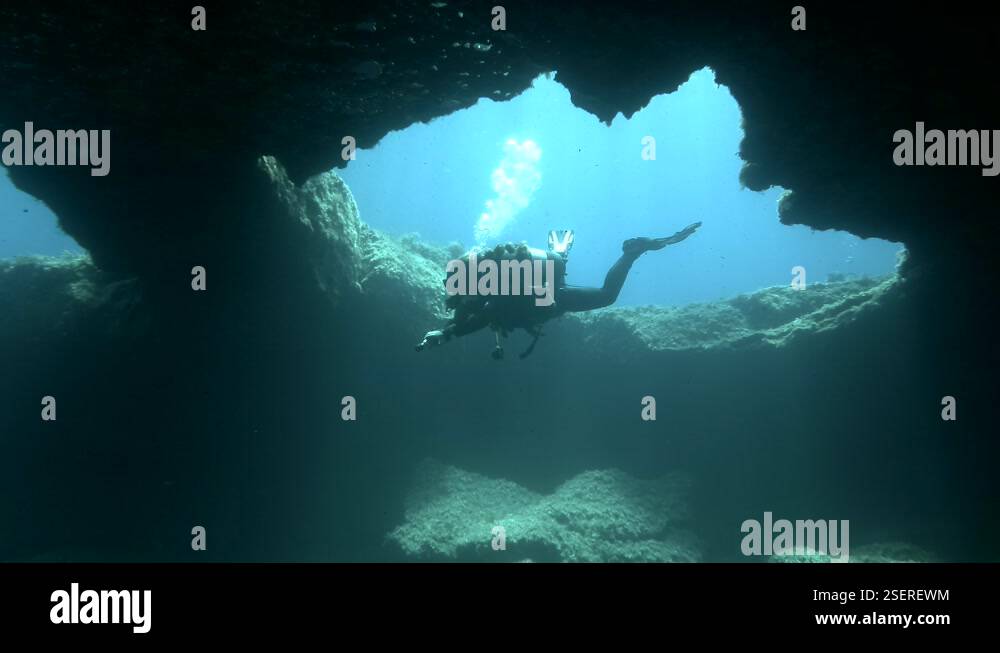 Female scuba diver swims in the cave. Cave diving in Mediterranean Sea ...