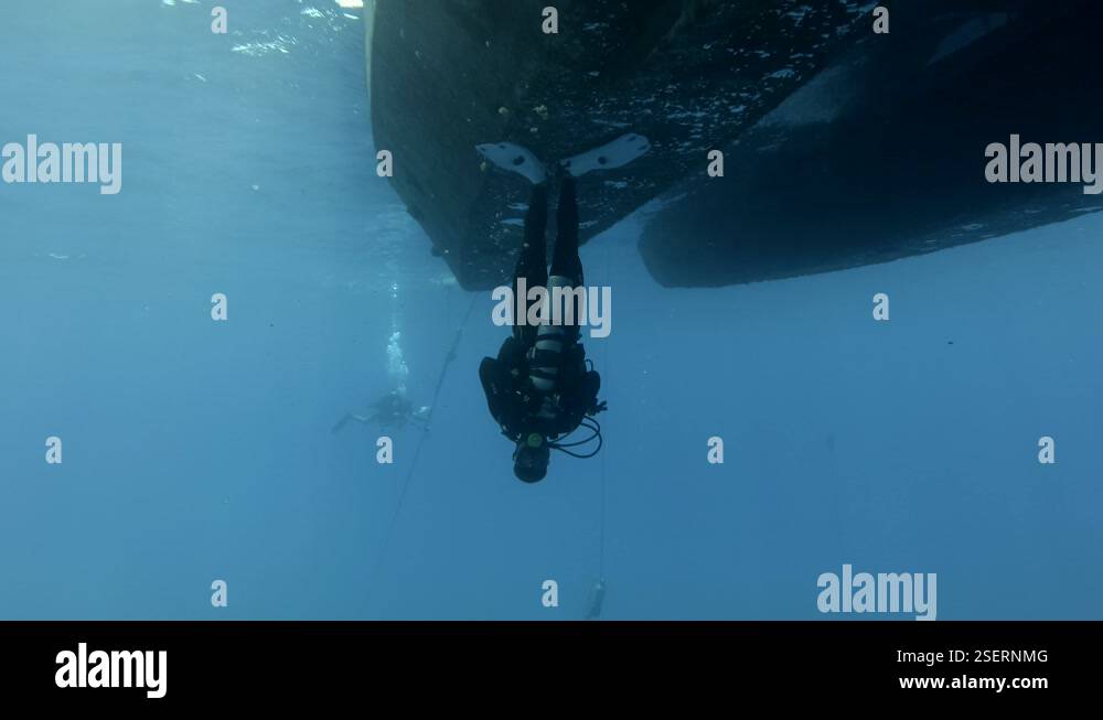 Scuba diver standing upside down on the bottom of the dive boat ...