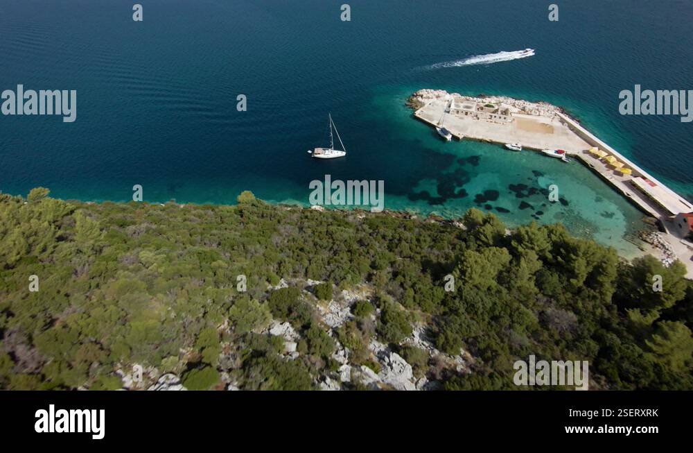 FPV Drone mountain surfing down to sea, blue water, bay dock with a ...