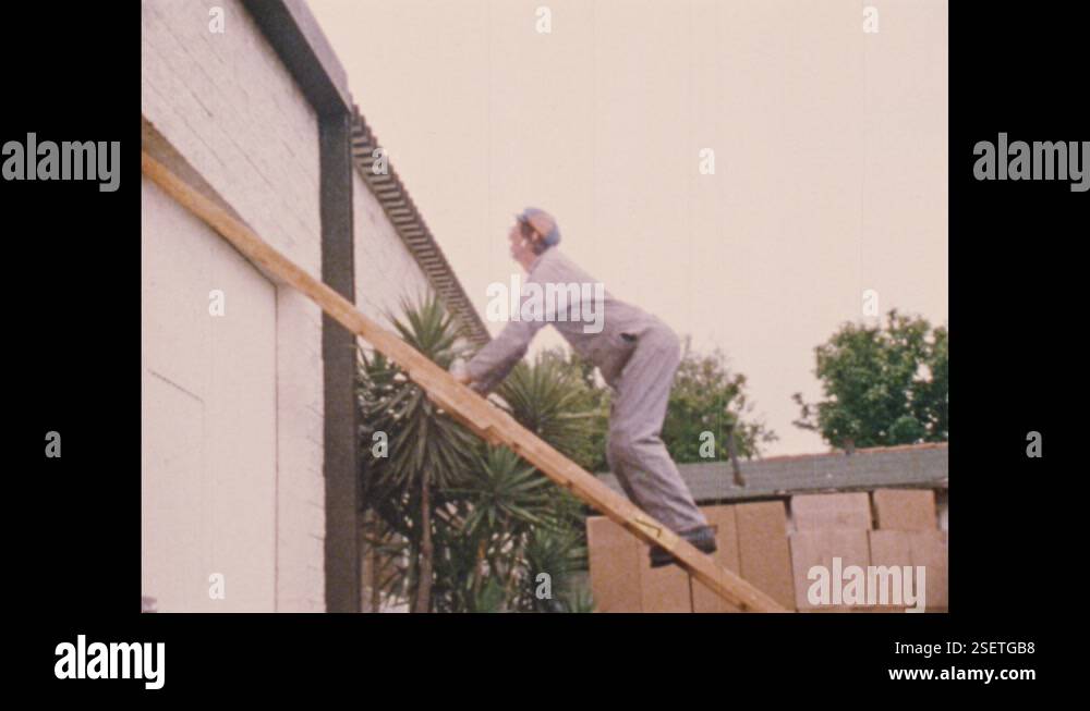 1970s: Man puts ladder at obtuse angle against warehouse wall. Ladder ...