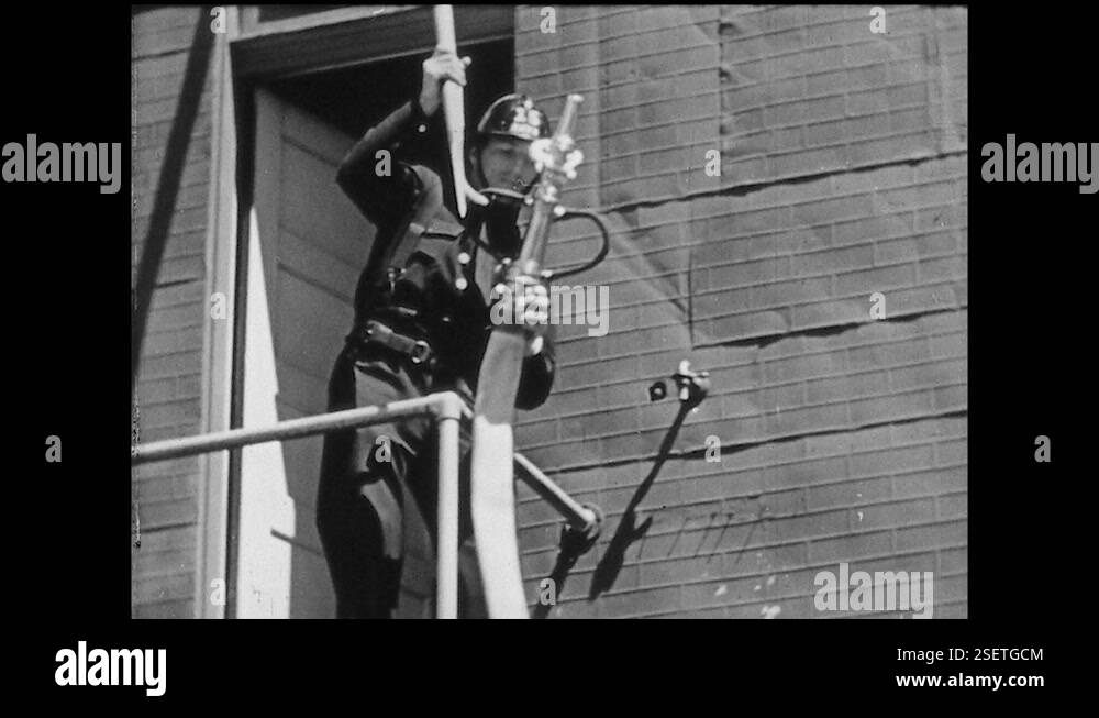 1940s: Firehose is lifted up building by rope to firefighter on landing ...