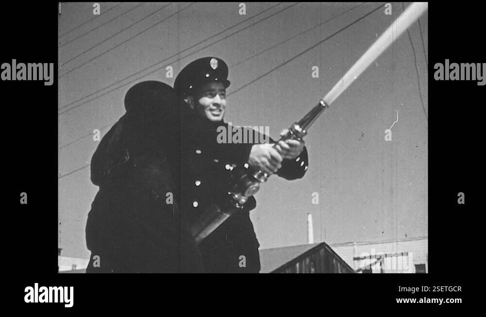 1940s: Firefighter on ladder with firehose, water stops spraying. Two ...