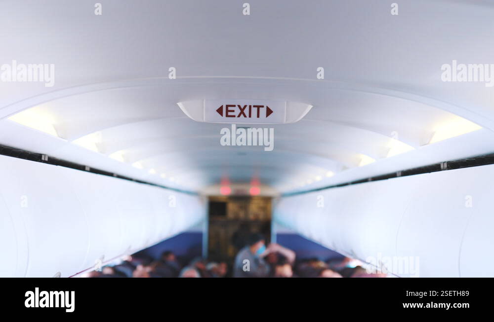 Interior Of A Large Modern Airplane With An Exit Sign - Passengers ...