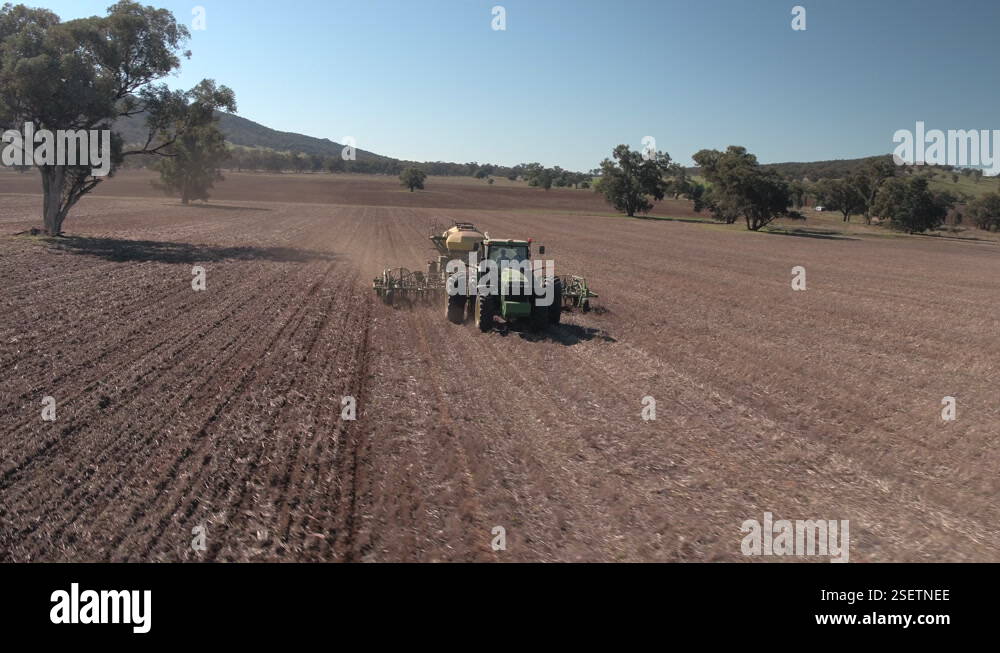 Low orbit aerial view of a Tractor towing an air seeder in a large ...