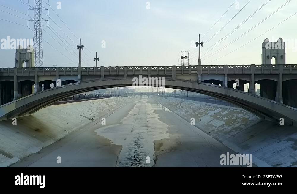 Push in under downtown LA river arch bridge viaduct urban storm sewer ...