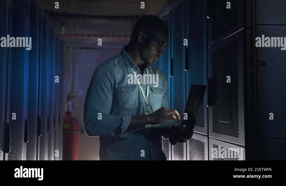 Young male engineer working with laptop hardware while standing in ...