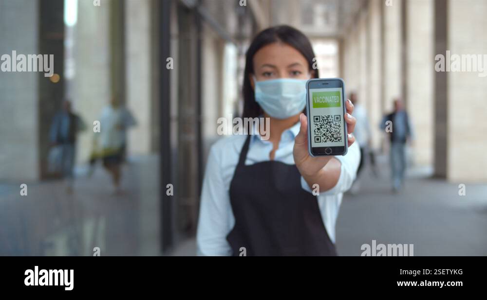 female restaurant owner in safety mask showing cellphone with ...