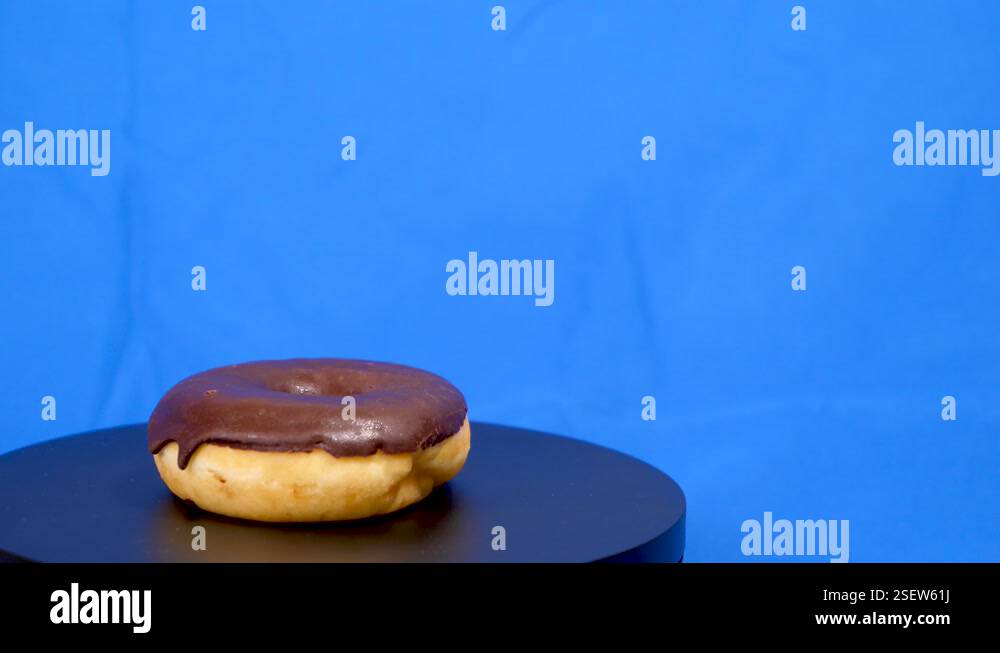 a chocolate donut turns around in a delightful way. the background is a ...