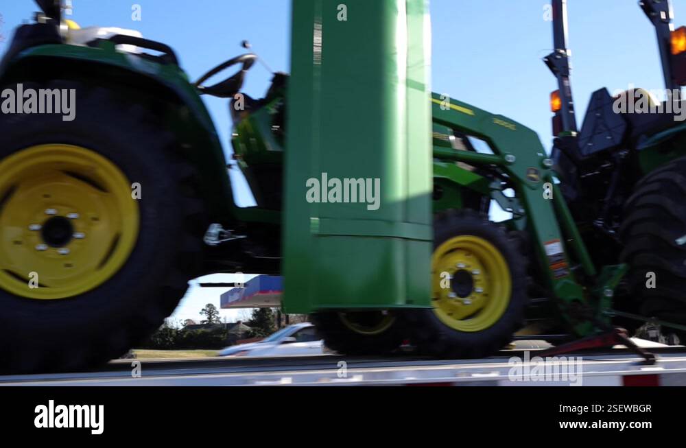 Pan of a semi truck hauling John Deere tractors clear blue sky ...