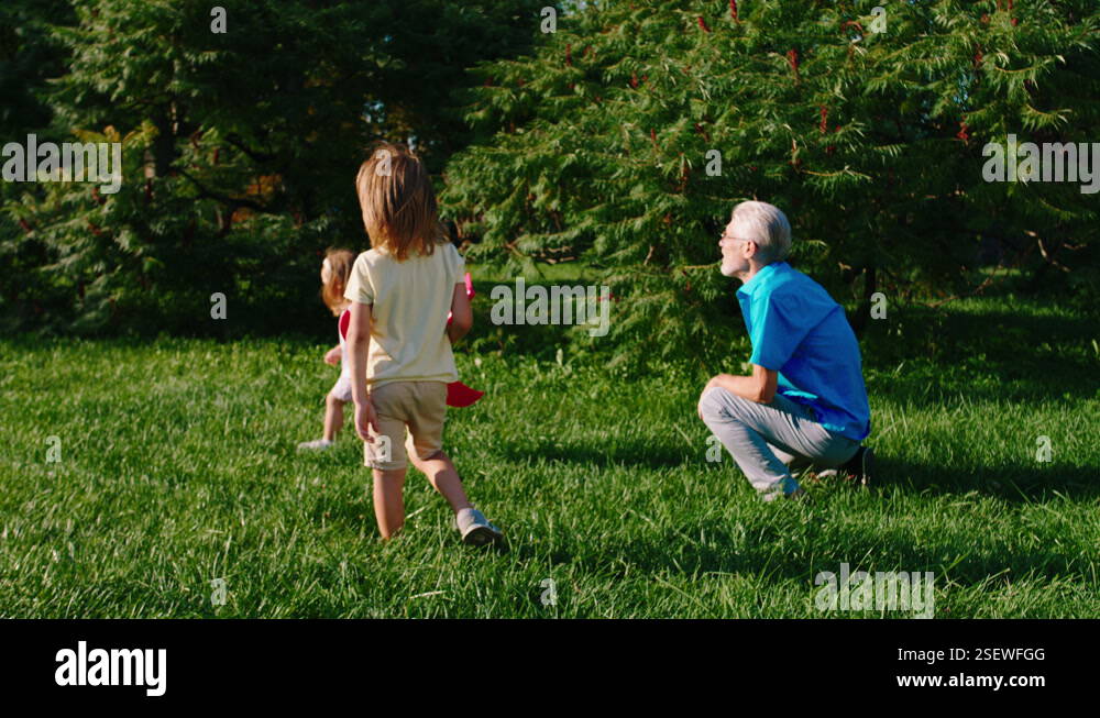 Old charismatic man playing with his nephews in the park in a sunny day ...