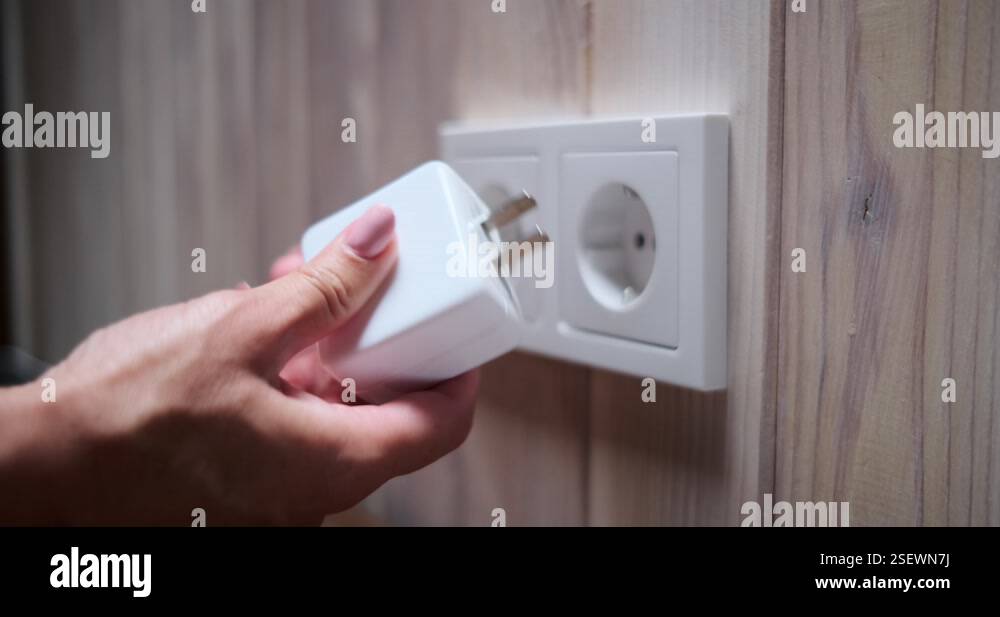 Human hand connecting charger to electric socket through adapter Stock ...