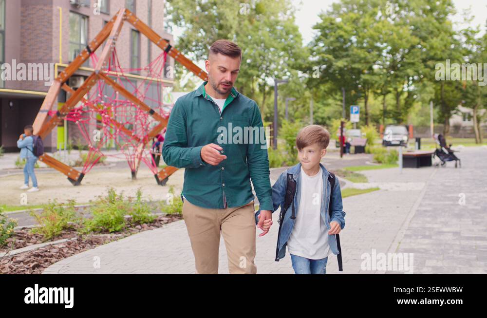 Loving father sending his son to school. Dan and child walk along ...