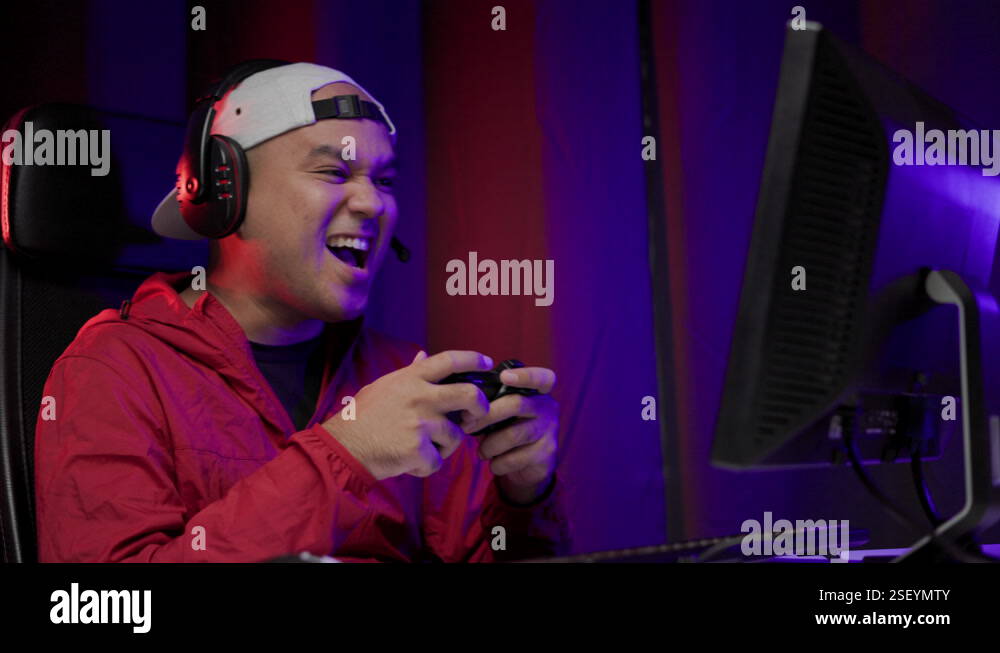 Excited and shocked face of Asian gamer with headphone holding joystick ...