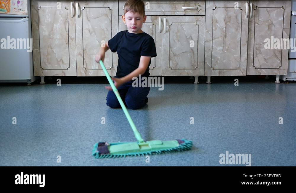 Happy Caucasian child 6 - 9 years old sitting on the floor mops the ...