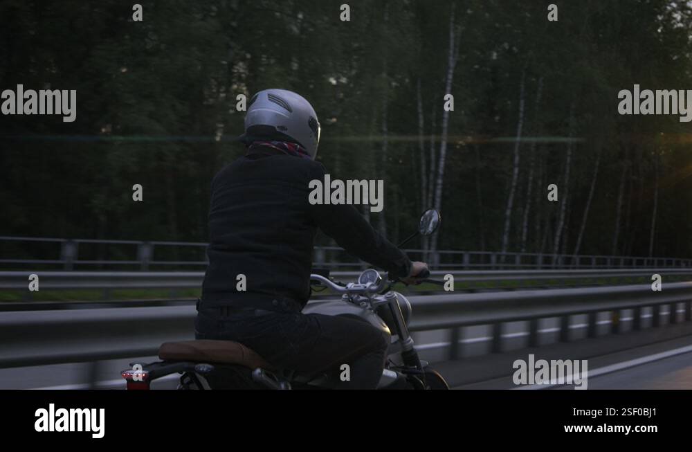 Man riding scrambler motorbike on the highway through the forrest at ...