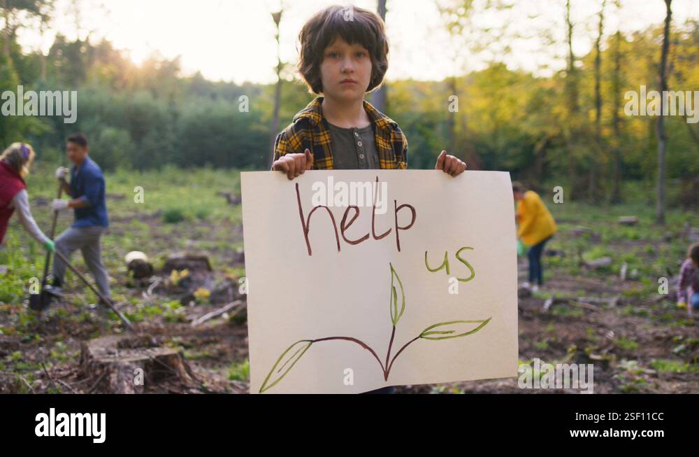 Little child boy holding carton placard with help us writing. Activist ...
