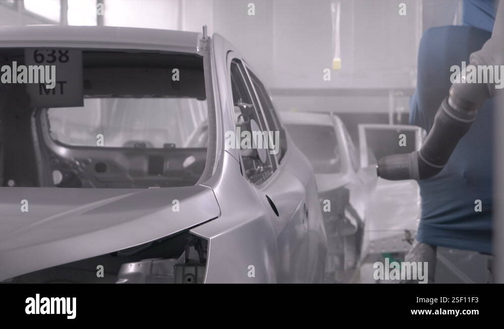 Robotic arms spray painting a vehicle body at a car manufacturing ...