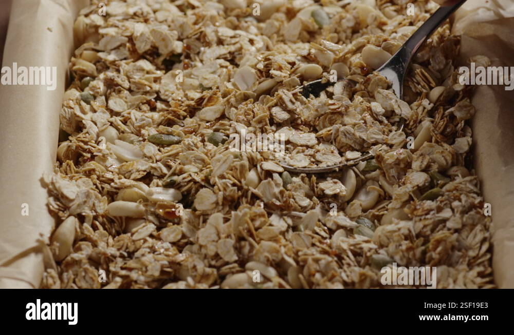 Slow motion making homemade granola mixing oats with nuts and seeds ...
