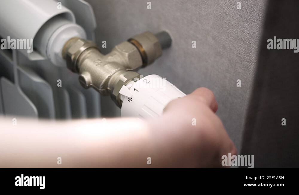 Person adjusts the temperature of the battery radiator at home, close ...
