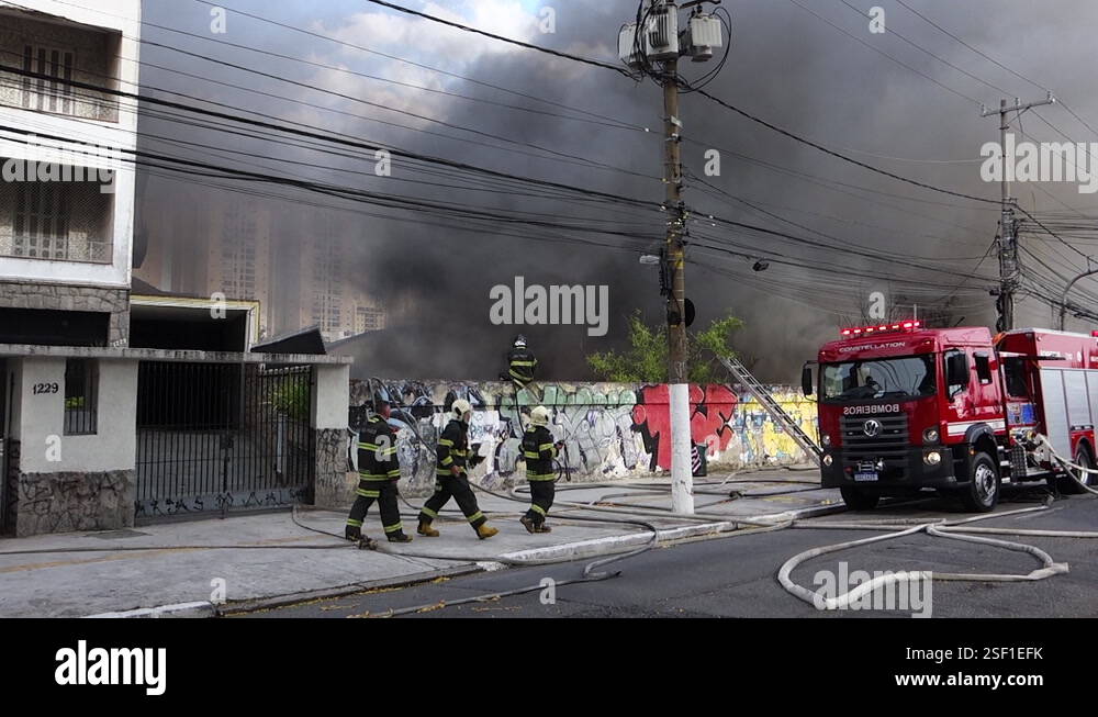 Slow pan right reveals fire apparatus at large urban fire in Sao Paulo ...