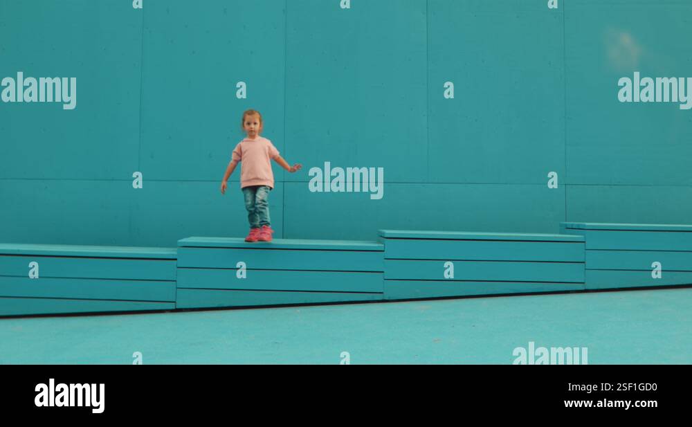 Cute shy little girl kid dancing outside on blue background. Funny ...